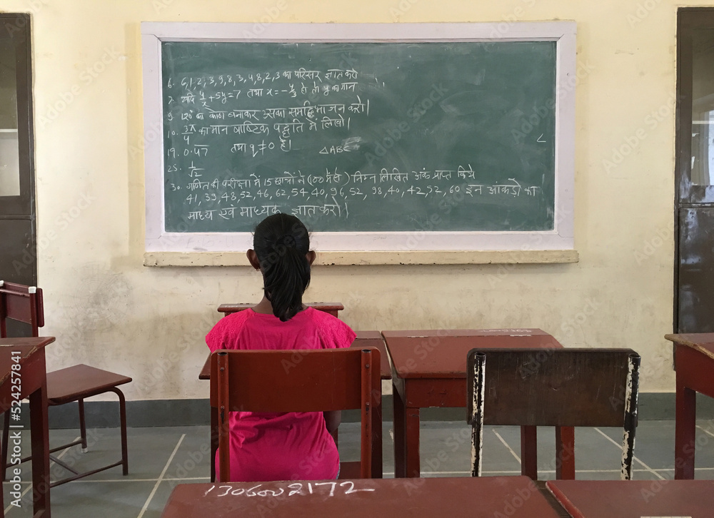 A young girl student looking at a blackboard with in the classroom. A ...