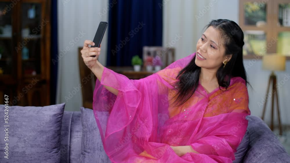 A young Indian housewife clicking a selfie with a victory gesture ...
