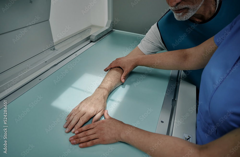 Radiologist doing X-ray of male patient's hand on modern X-ray machine ...