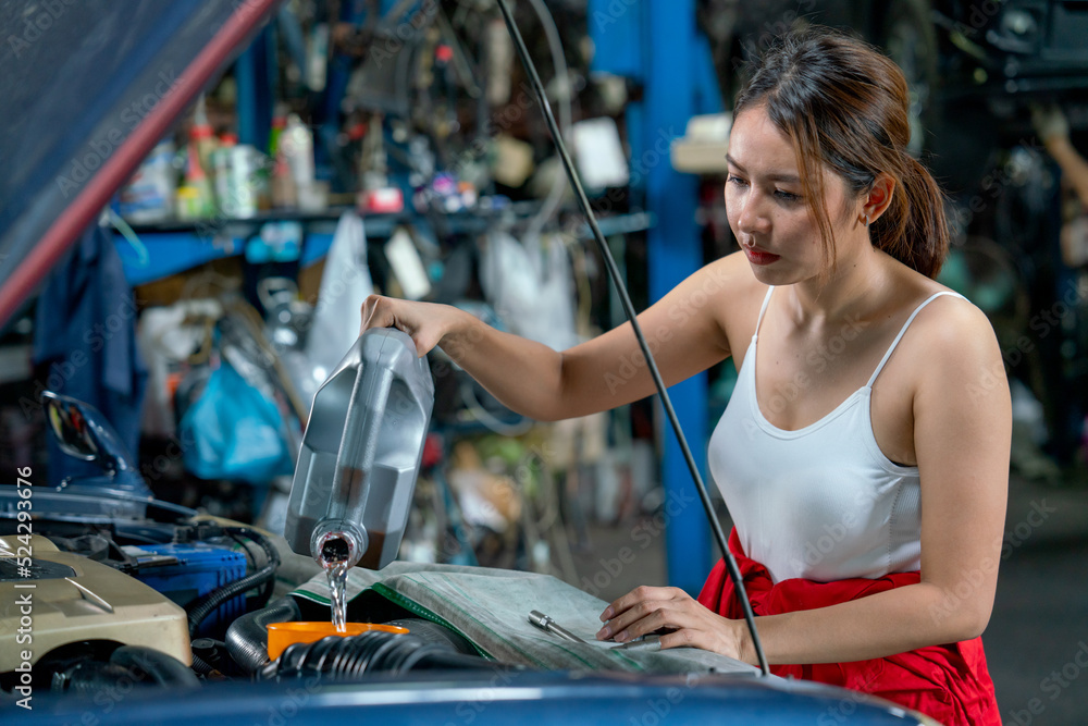 Foto de Asian mechanic woman take care engine of car by filling some ...