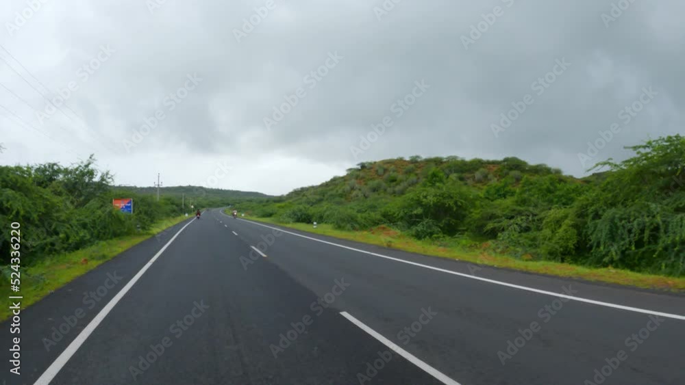 Hyperlapse of road covered with green grass and dark clouds in sky at ...