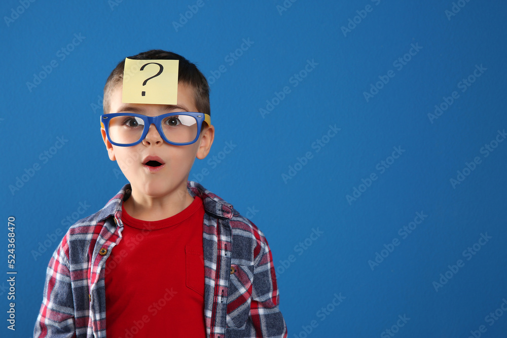 Emotional little boy with question mark on blue background, space for ...
