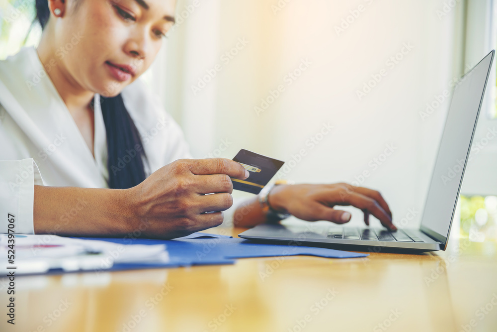 Young woman entering credit card number on laptop computer shopping ...