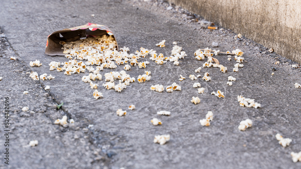 Popcorn in a cardboard box lies on concrete ground outside. The man ...