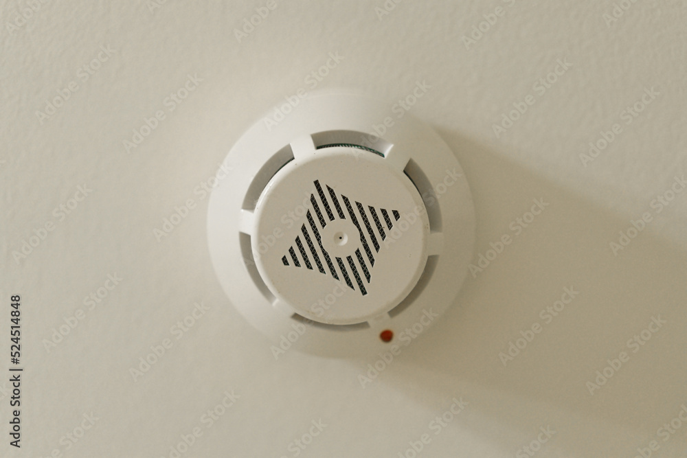 White smoke detector fire alarm on a white ceiling. Indicator. White ...