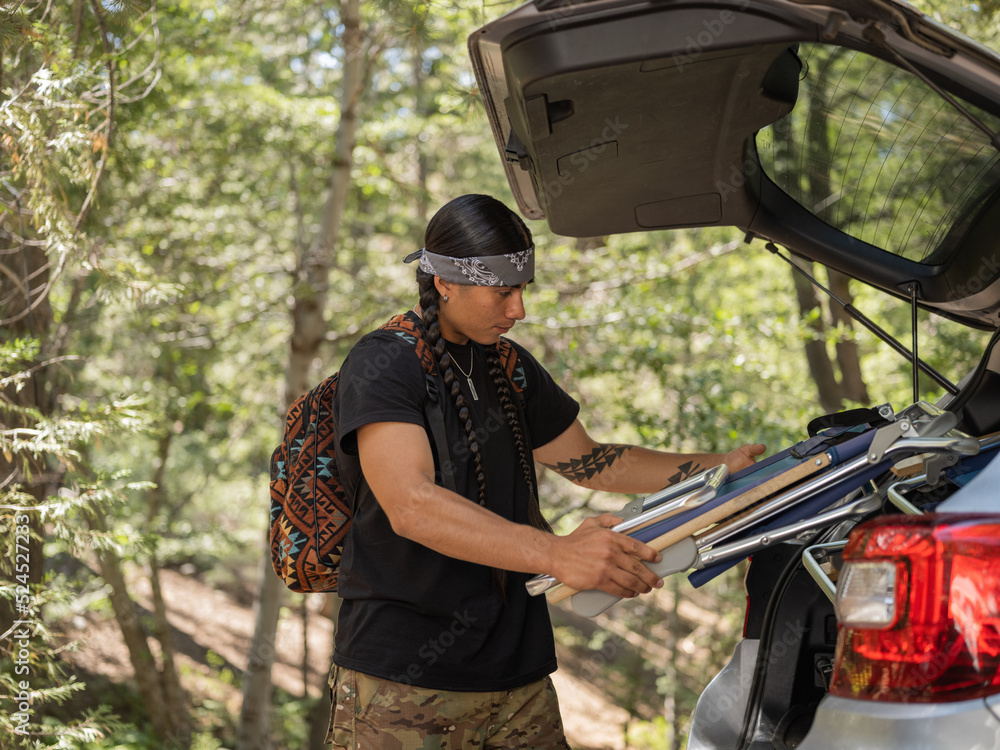 Indigenous young man unloading a car in nature Stock Photo | Adobe Stock