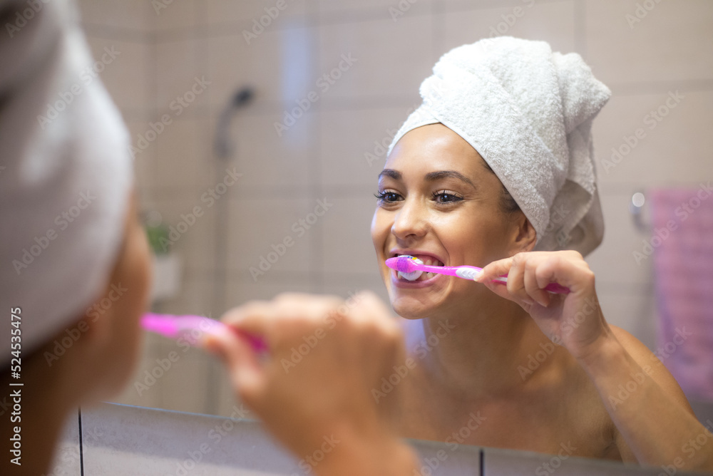 Foto de Young woman washing teeth in the bathroom in front of the ...