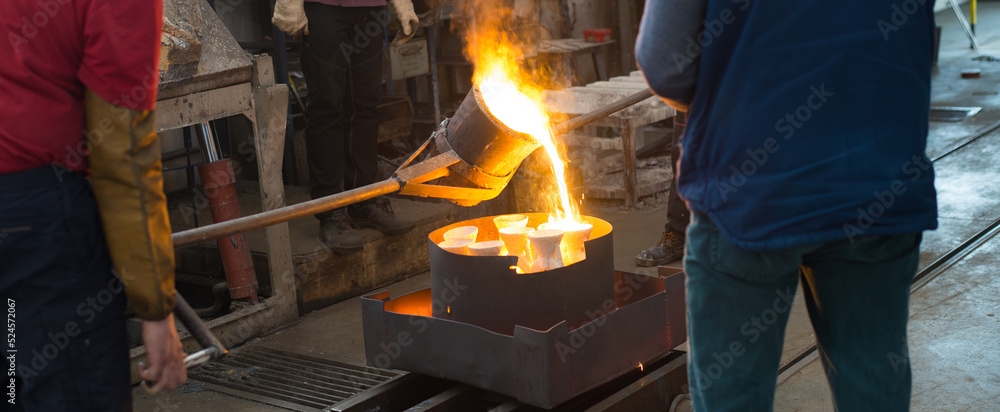 Workers molding objects in the foundry, pouring melted metal in molds ...