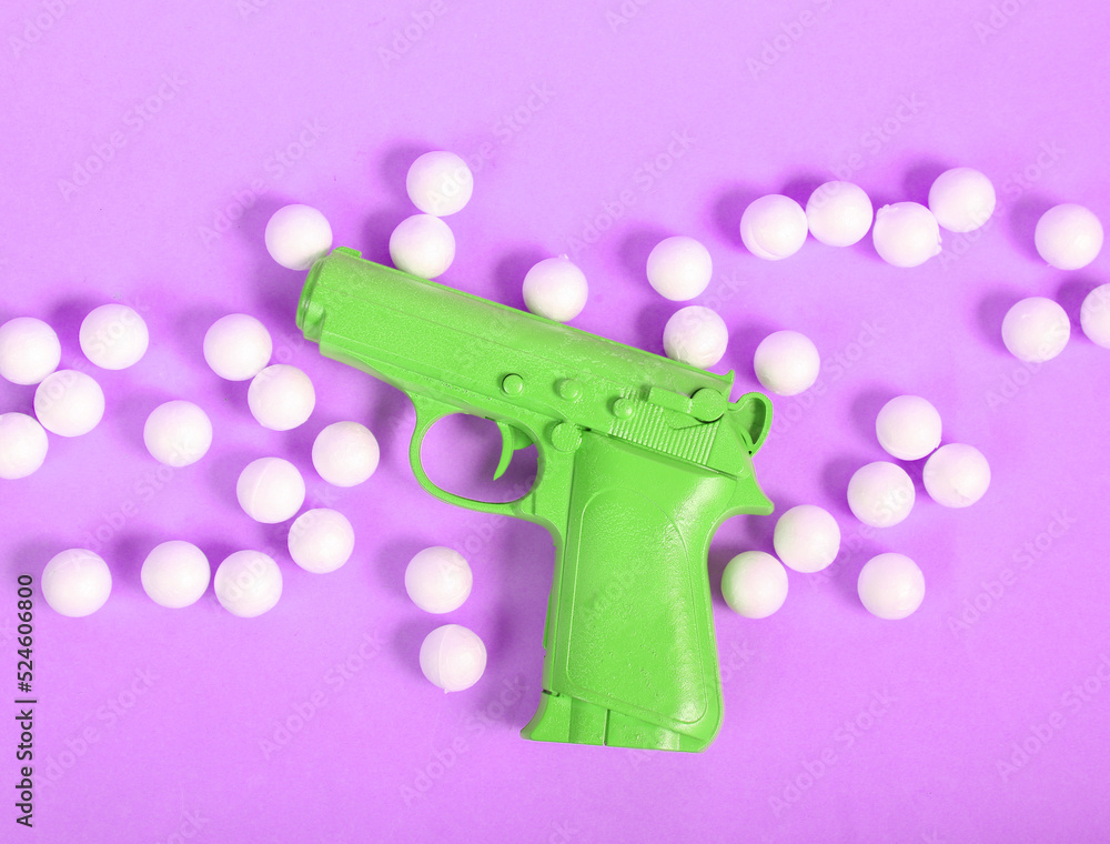Pink gun with white balls on purple background. Minimalism still life ...