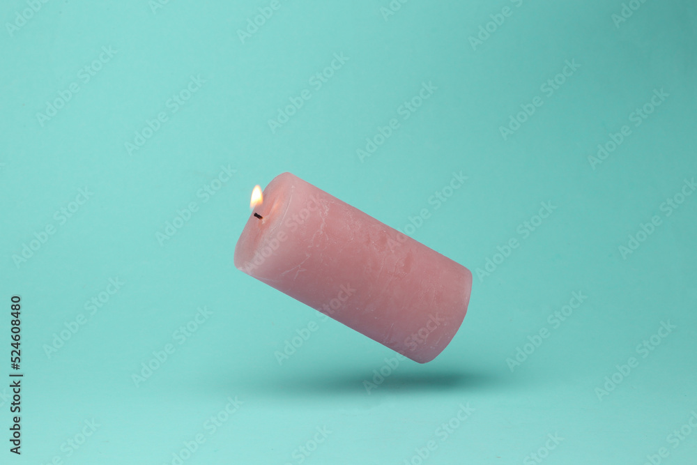 Pink flaming candle flying in antigravity on mint green background with ...