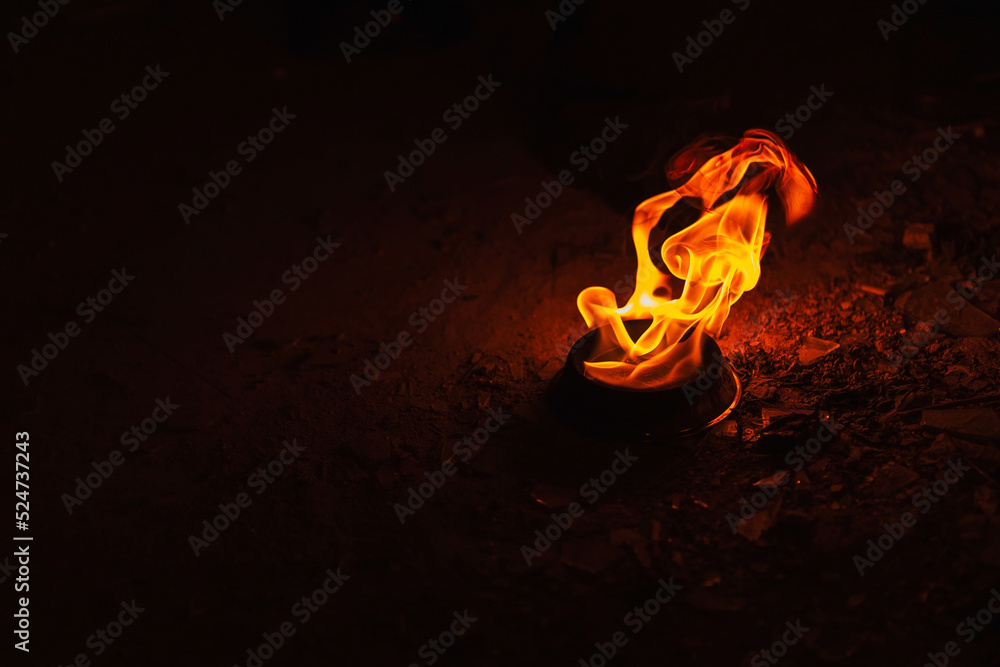orange fire on a dark background. Burning kerosene in an iron plate. a ...