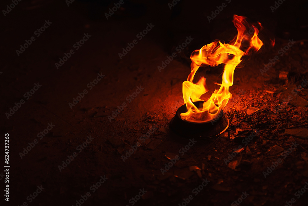 orange fire on a dark background. Burning kerosene in an iron plate. a ...
