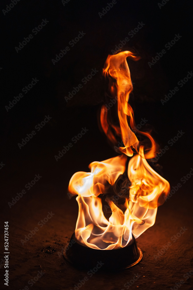orange fire on a dark background. Burning kerosene in an iron plate. a ...