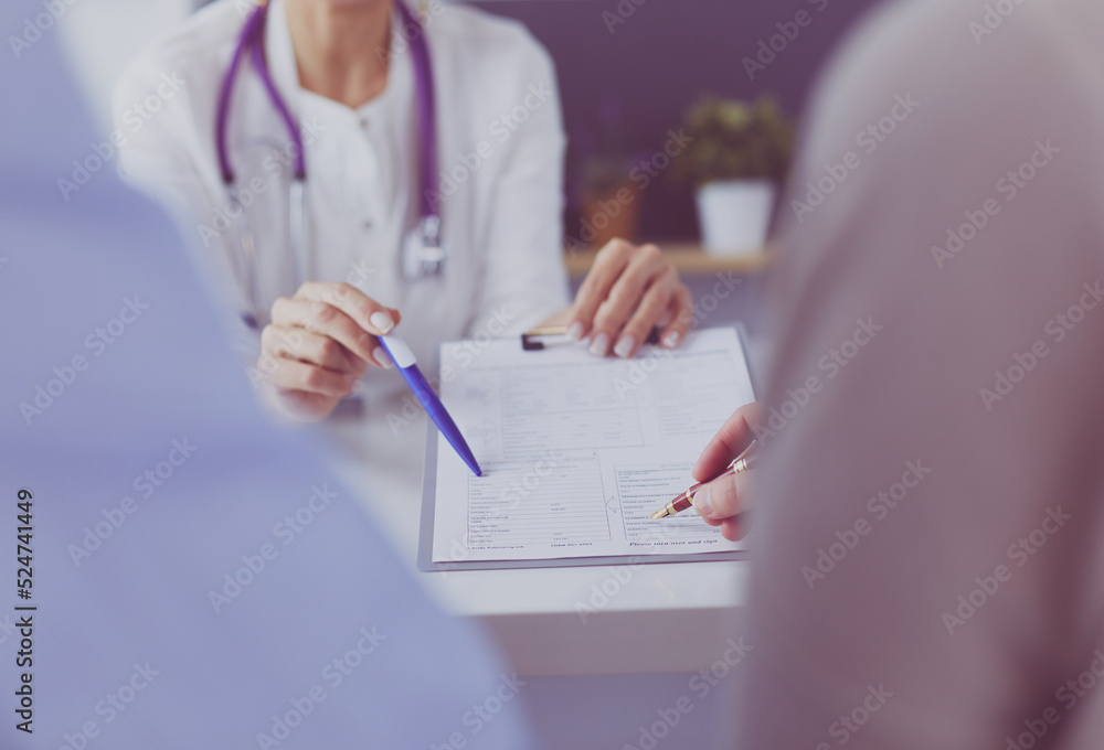 Doctor and patient examining a file with medical records, she is ...
