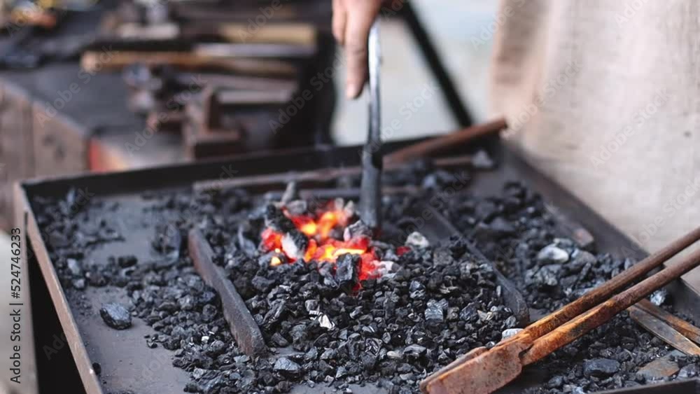 The hands of a caucasian male blacksmith of the middle ages turn ...