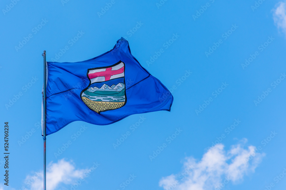 Canada Alberta provincial flag waving on a flagpole against blue sky ...