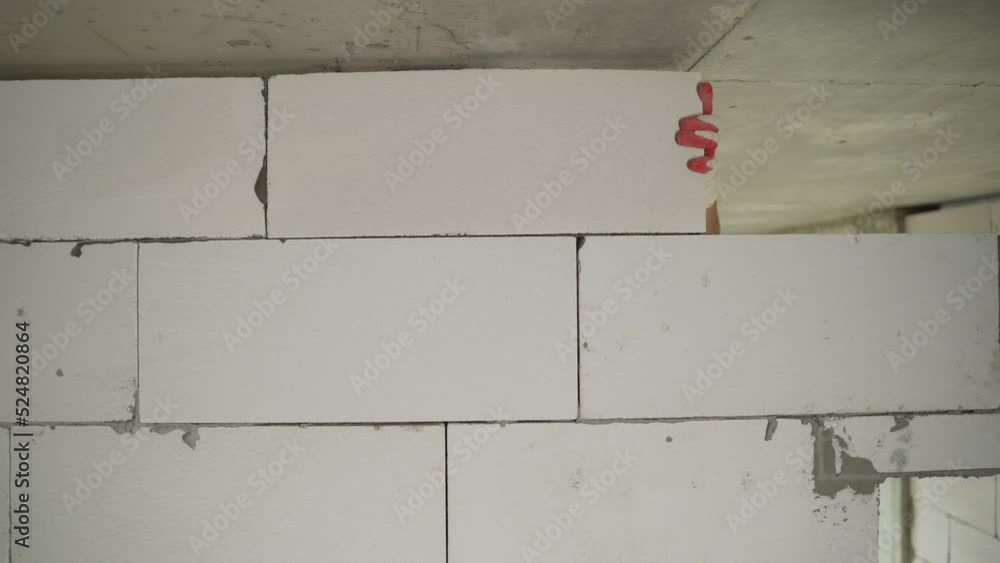 Worker at the construction site. Professional builder laying blocks ...