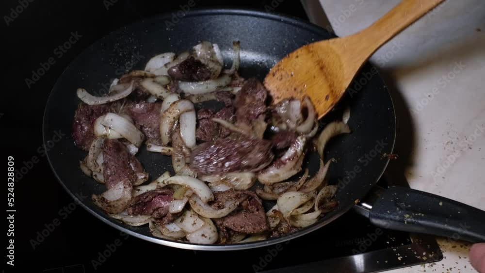 Chopped, half-ready onion and liver in hot oil. Stirring the pieces ...