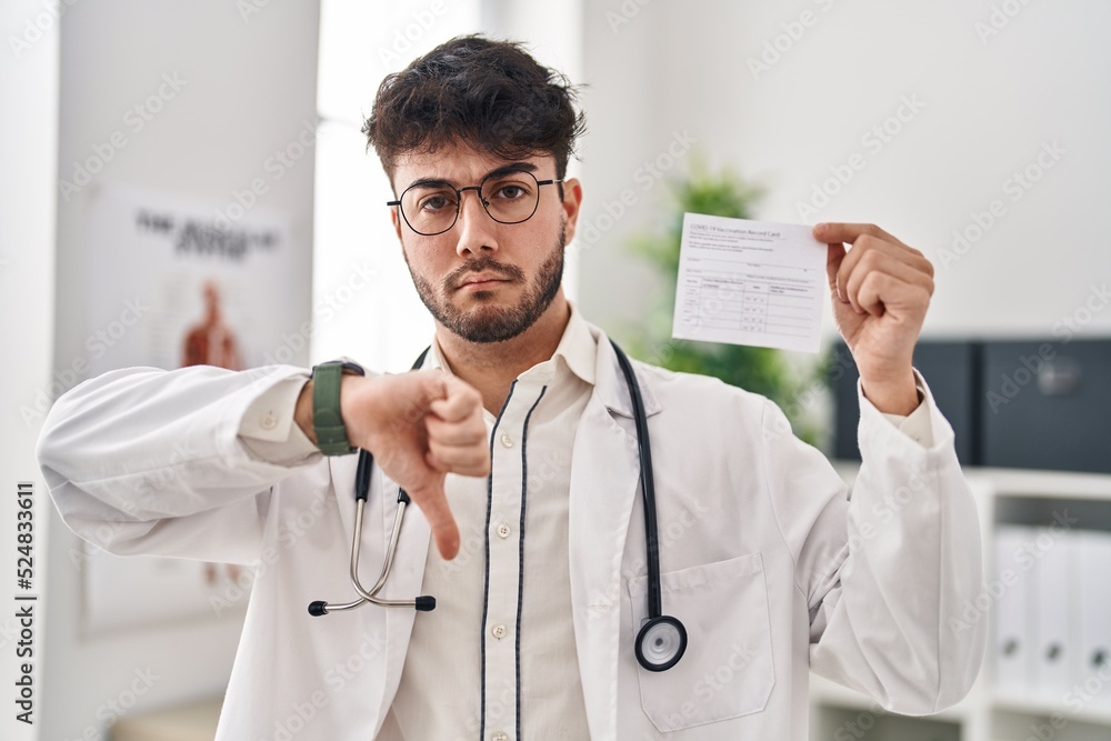 Hispanic doctor man with beard holding covid record card with angry ...