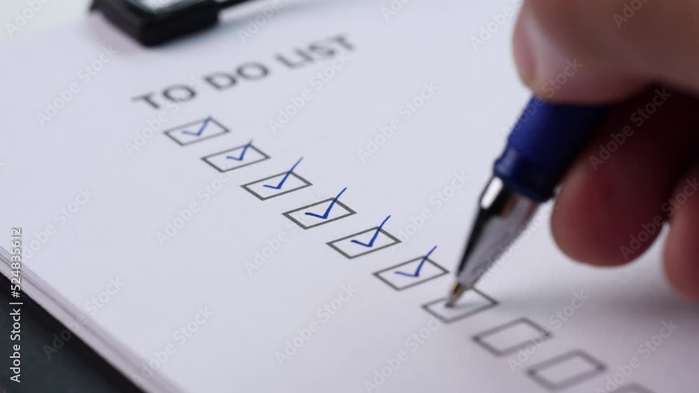 Close-up businessman tick off or marking with blue pen on checklist ...
