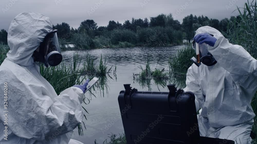 Scientists in safety uniforms, sampling river water for analysis ...