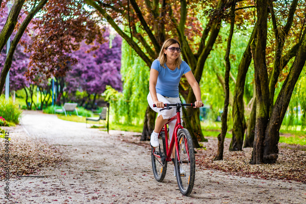 Woman riding bike in city park Stock Photo | Adobe Stock