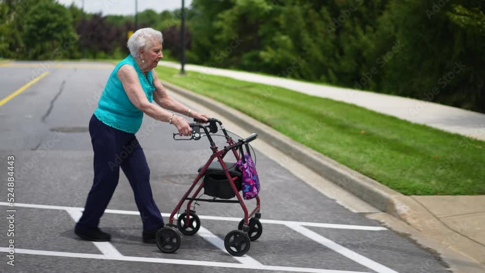 Elderly senior woman pushing a walker at pedestrian crossing with stop ...