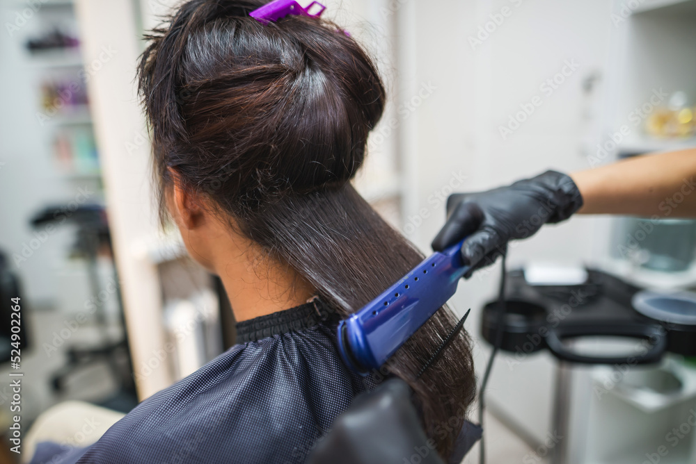 Hairdresser using a hair straightened to straighten the hair. Hair ...