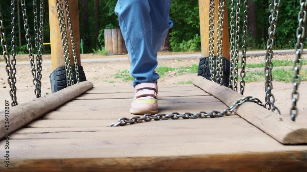 Children's feet in sneakers and jeans on a playground with a swinging ...