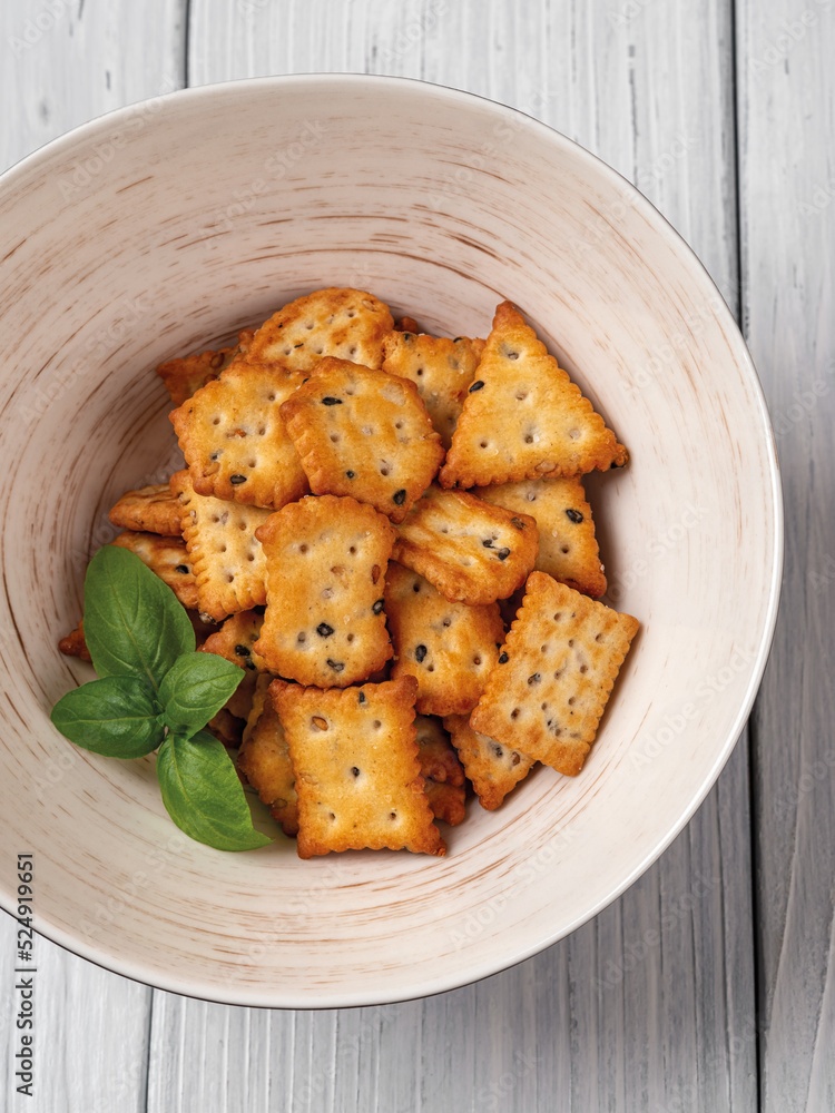 Some saltine crackers in a bowl on a white wood background. Ready to ...