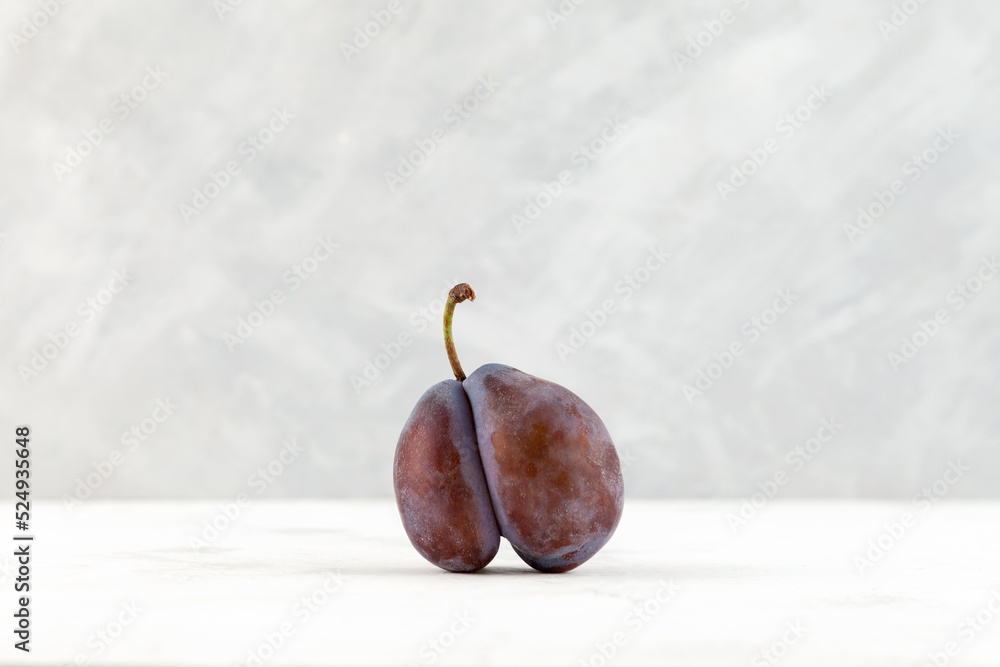 Deformed Fused fruit, ugly prune on grey background. Double fruit. Food ...