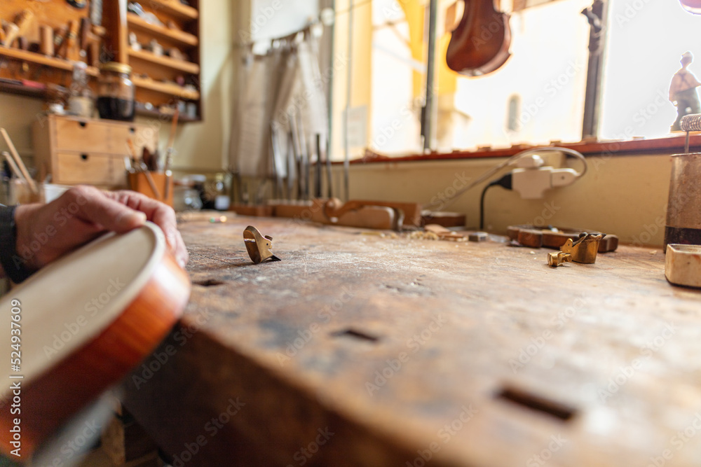 luthier carving the shape of the outside of the front of a violin with ...