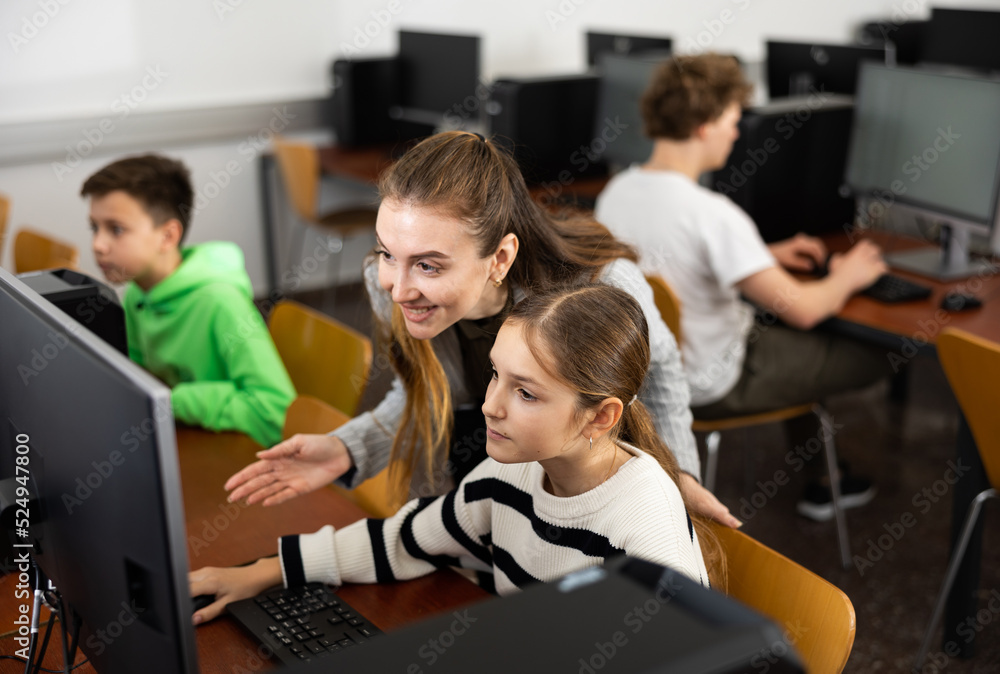 Female teacher and her student, young girl, looking at monitor of PC ...