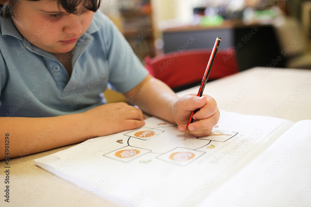 girl with short and curly hair looking down and writing on her school ...