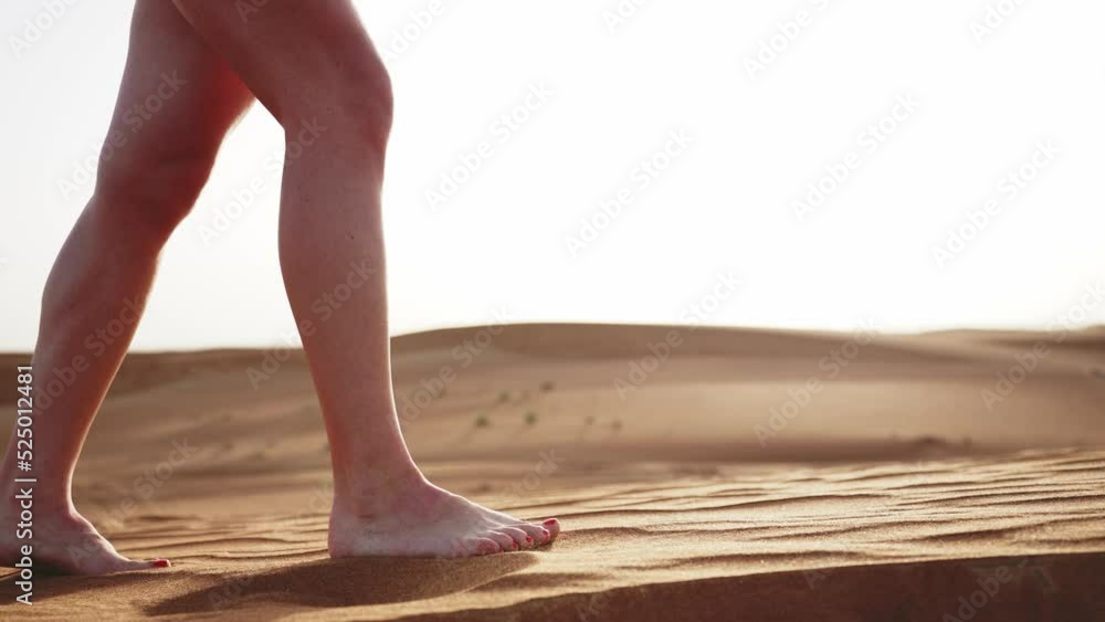 Close-up beautiful female legs in shorts walking on desert sand ...