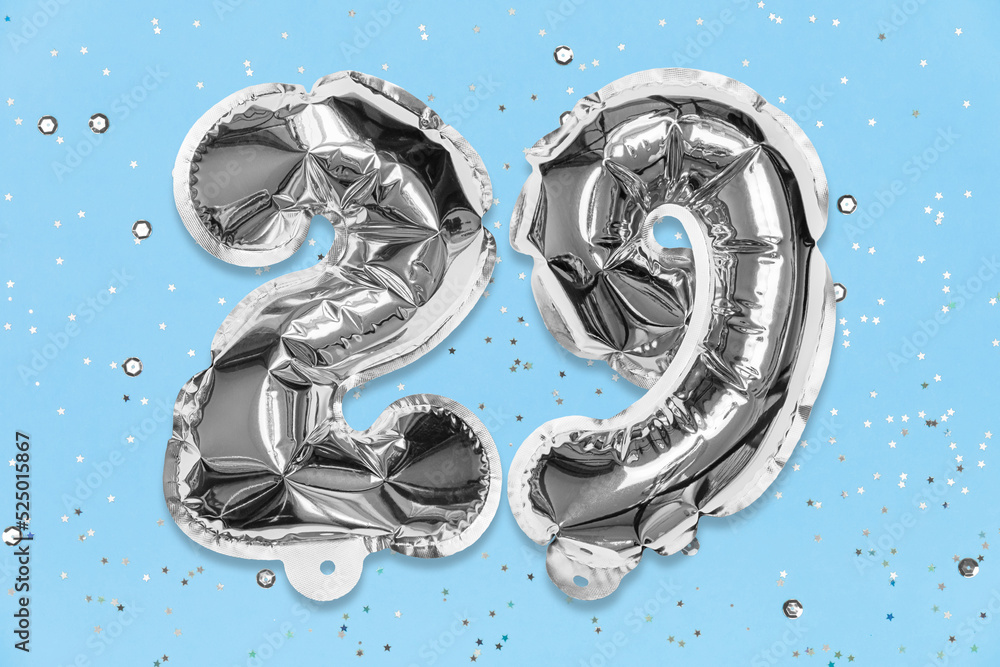 Silver foil balloon number, digit twenty nine on a blue background with ...