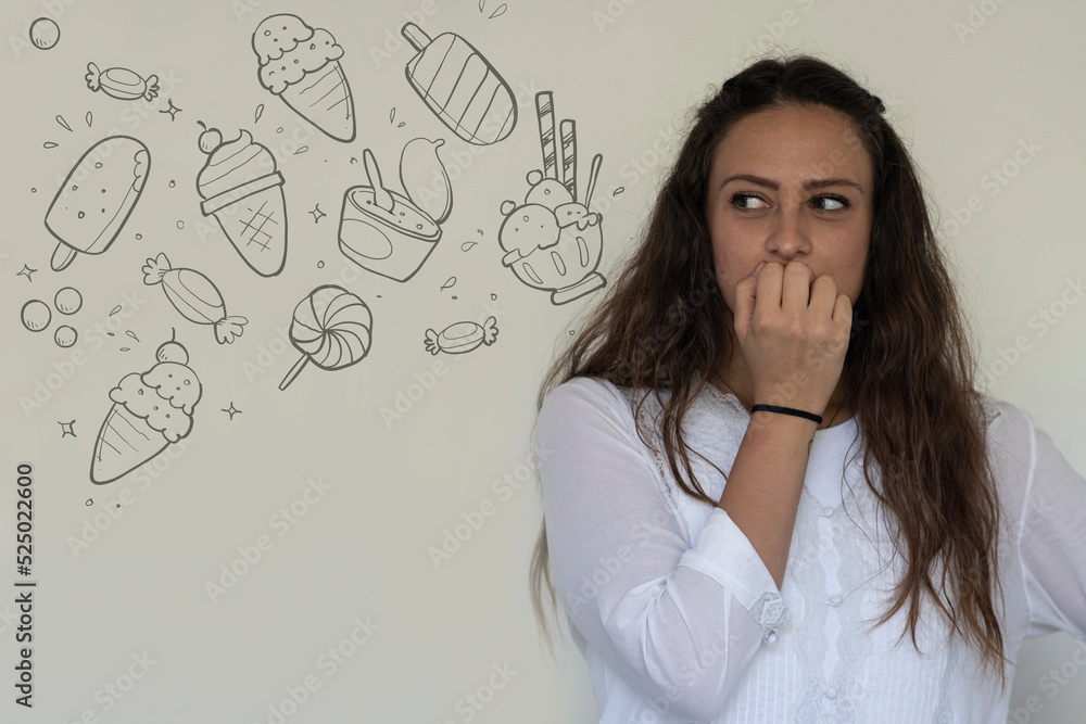 Beautiful girl tries to resist the temptation of candy and ice cream ...