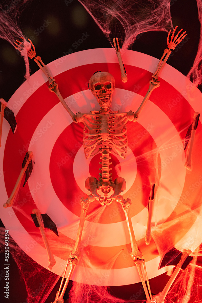 crucified skeleton with axes in red neon light on the target. Halloween ...