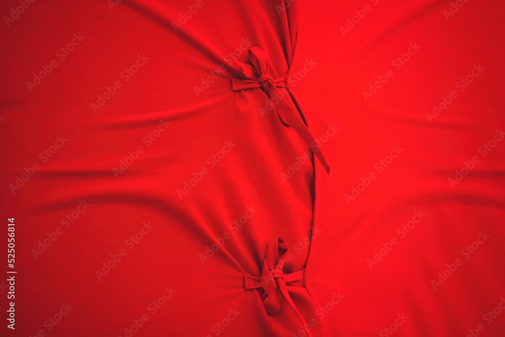 Dark deep red background of creased material with cute ribbons tied up ...