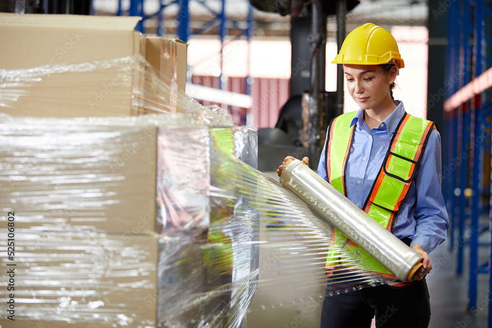 factory worker or warehouser wrapping stretch film parcel on pallet ...