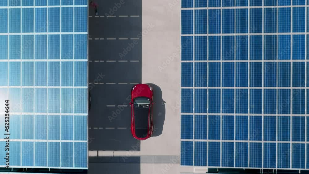 Overhead shot of red electric car driving by charging station. Electric ...