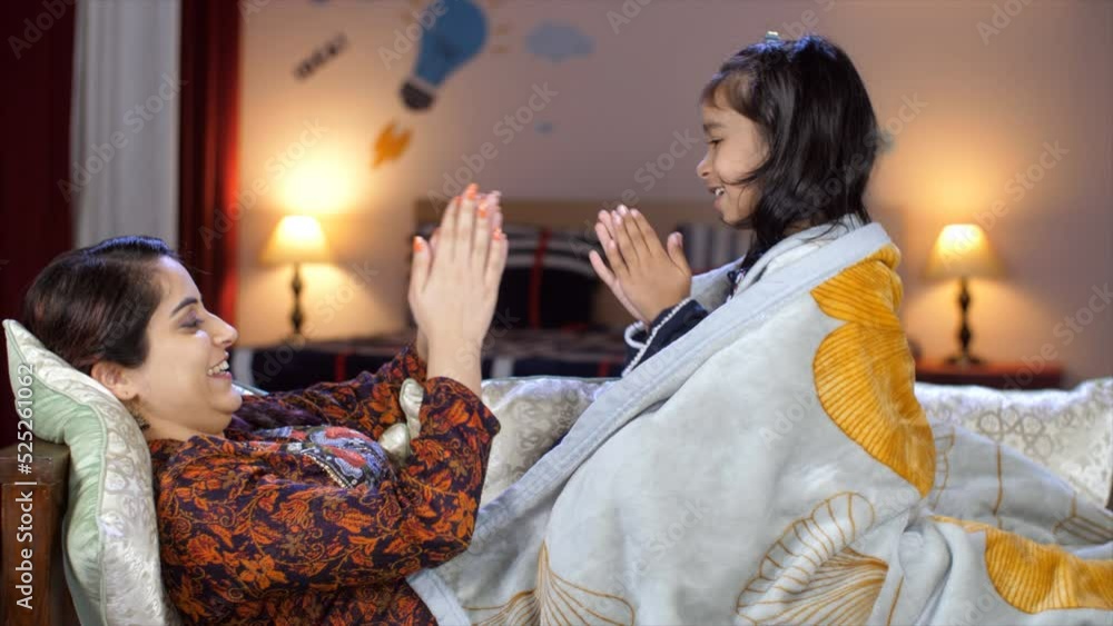 A cheerful Indian mother is playing hand-clapping games with her little ...