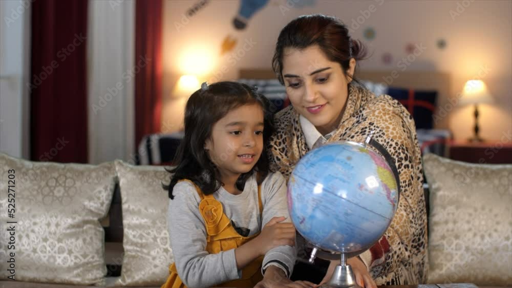 Indian mother and daughter checking different places on a world map ...