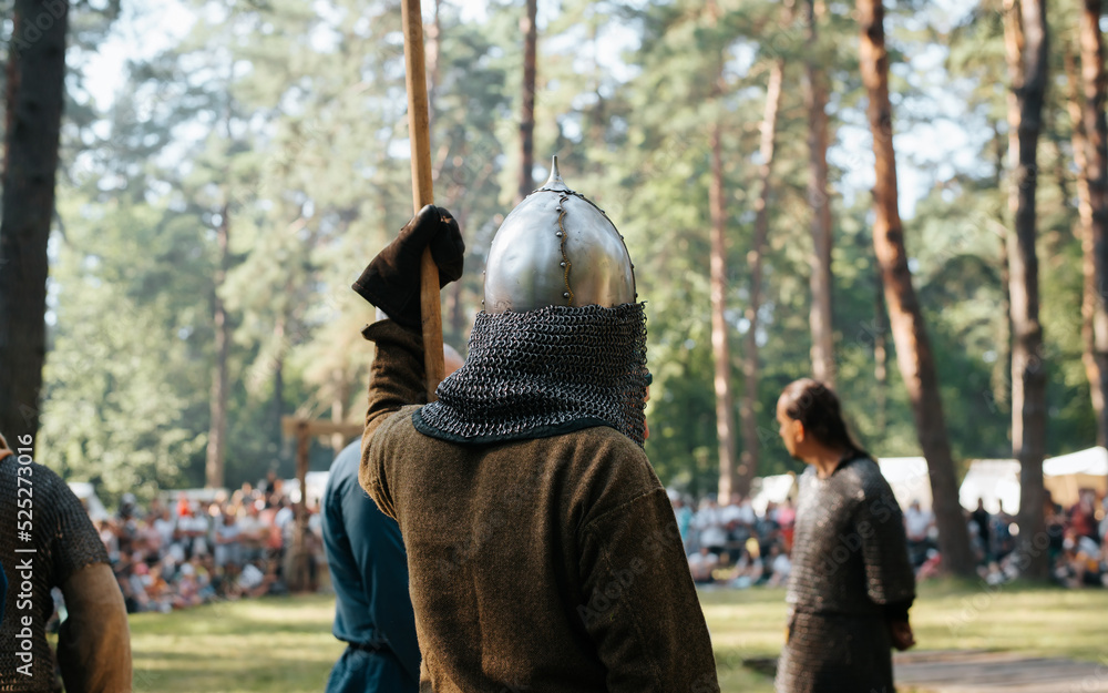 Rear view of an unrecognizable knight warrior in helmet and with spear ...