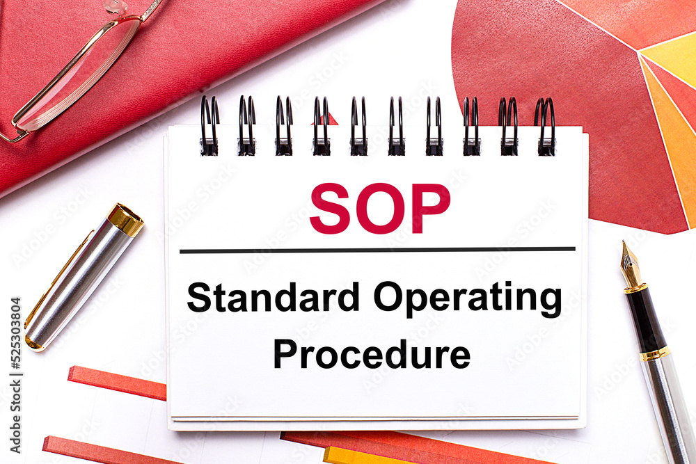 On the desktop is a white notebook with the text SOP Standard Operating ...