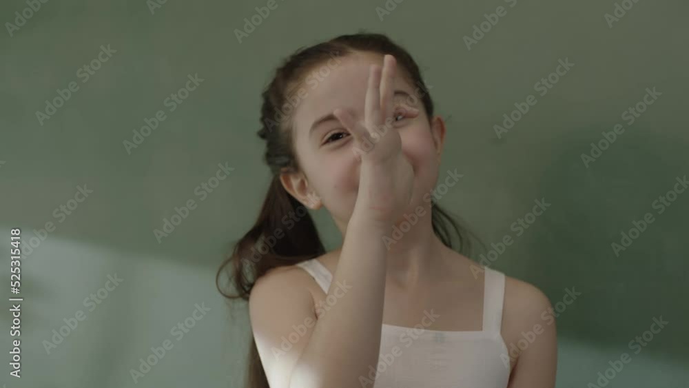 Little girl having fun, making fun by putting her hands on her nose ...