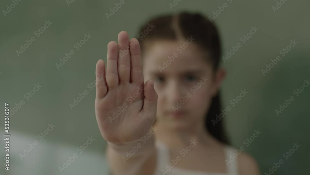 Little girl makes a stop sign with her hand and says stop to social ...
