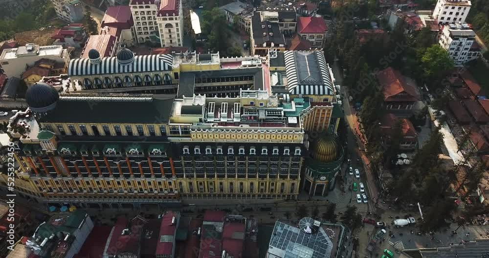 Aerial shot flying over the top of an ornate hotel building reveals an ...