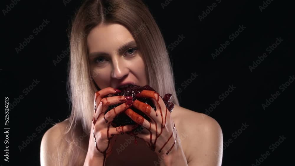 Young attractive blonde woman eating a heart, blood dripping from her ...
