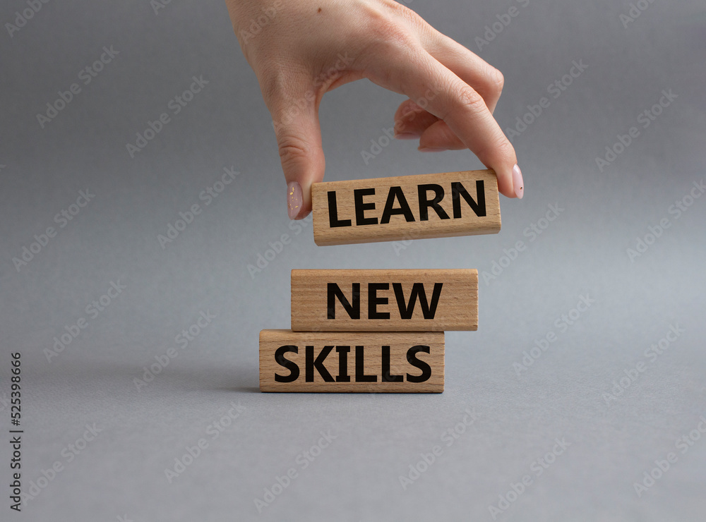 Learn new skills symbol. Concept words 'Learn new skills' on wooden blocks. Beautiful grey ...